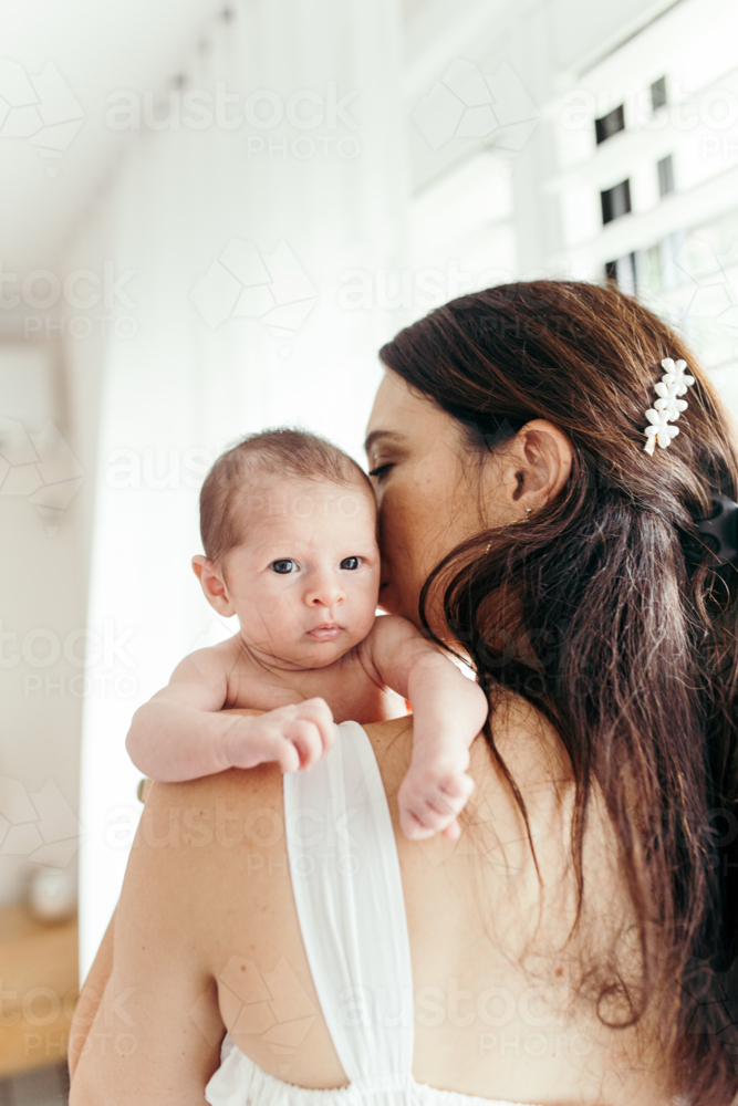 Image of Mother holding a newborn baby girl upright on her shoulder ...
