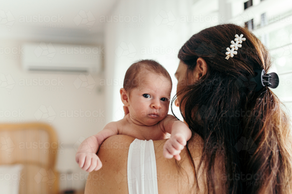 Image of Mother holding a newborn baby girl upright on her shoulder ...