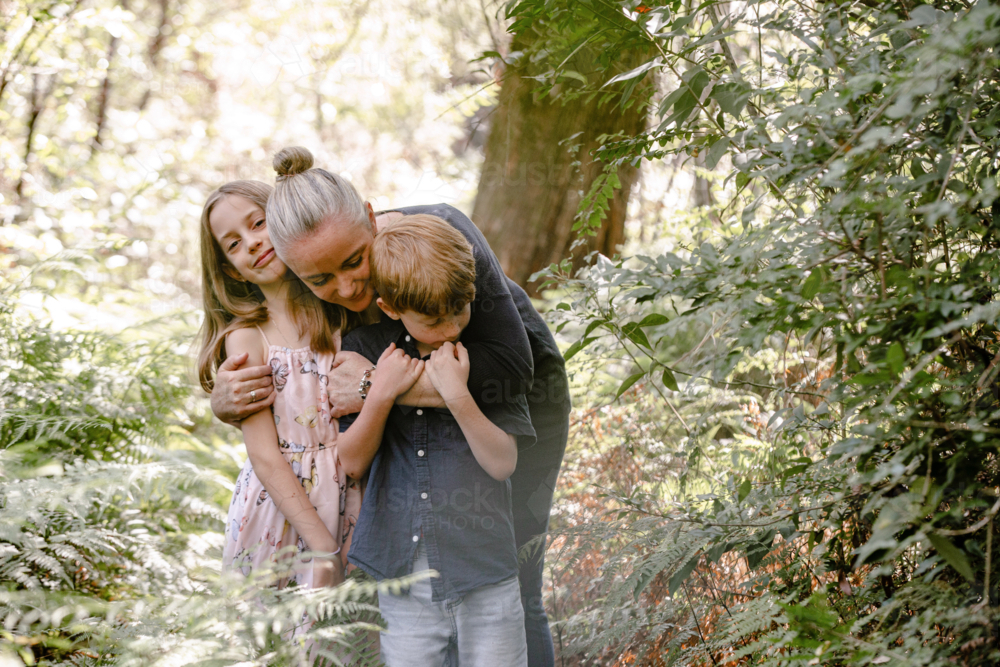 Image of Mother hugging children in bushland - Austockphoto
