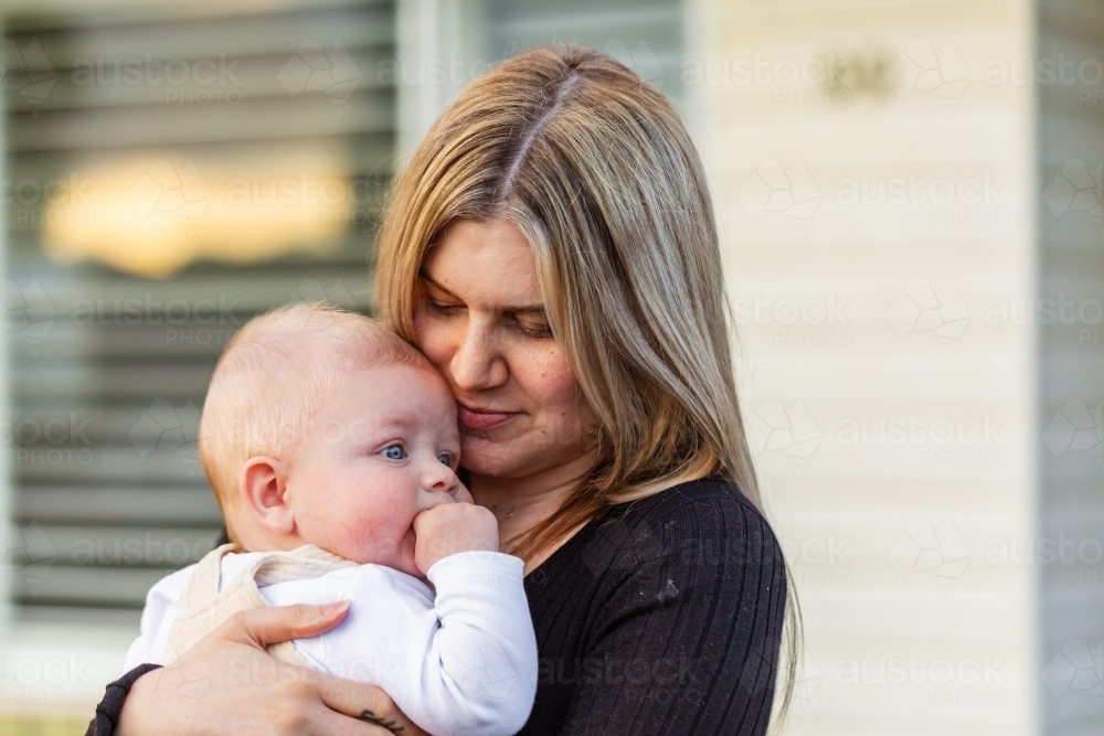 Image of mother looking down holding five month old baby in pastel ...