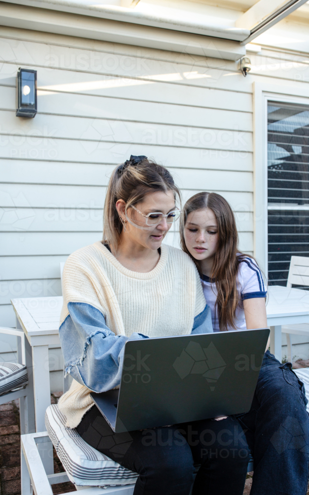 Image of Mother working on her laptop in the garden with her tween ...