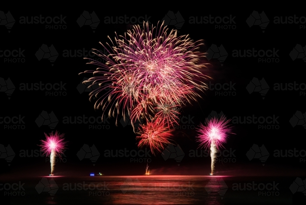 Image of Multi coloured fireworks exploding over an ocean in the night ...