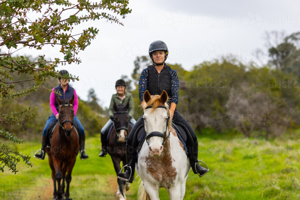 Image of Multi-generation women riding horses along a narrow dirt path ...