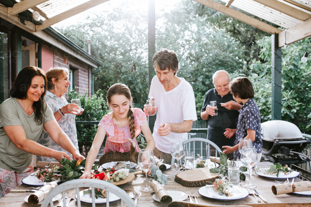 Image of Multigeneration family busy preparing the table for dinner ...