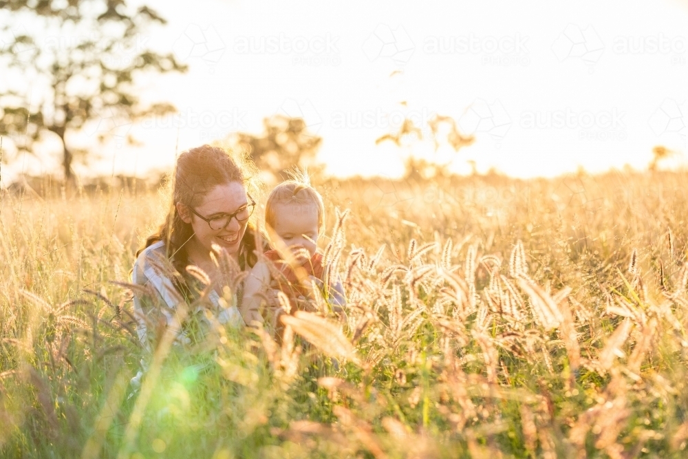 Image of Mum and baby girl sitting together seen through long grass in ...