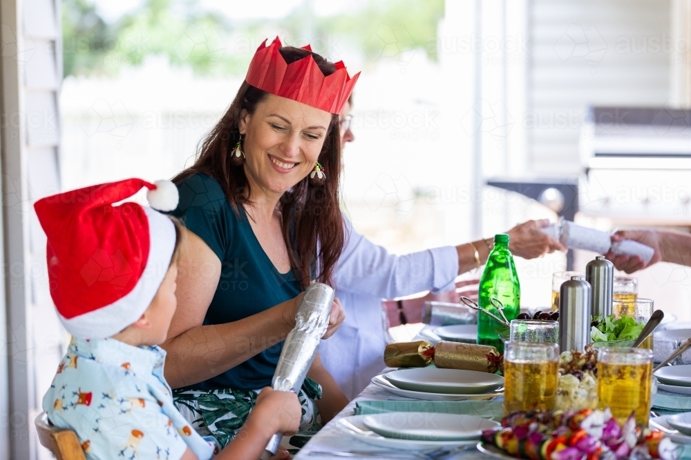 Image of Mum and son cracking bon bon at Christmastime - Austockphoto