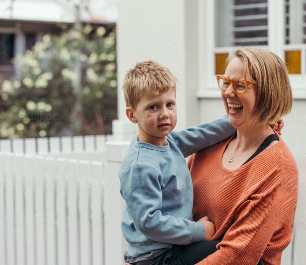 Image of Mum laughing holding son outside home - Austockphoto