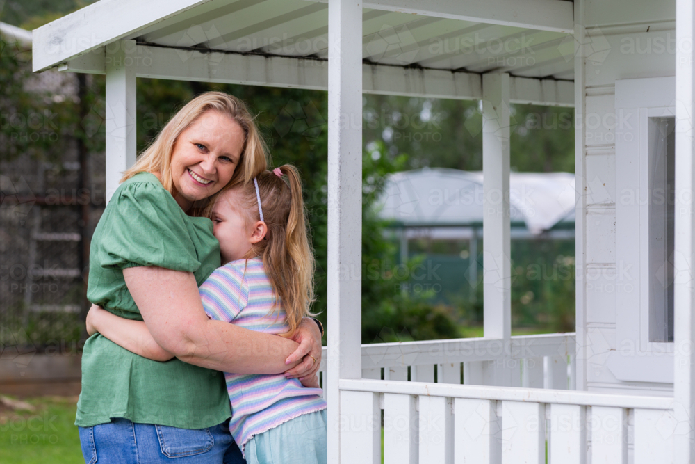 Image of Mum together with daughter hugging by cubby house on farm ...