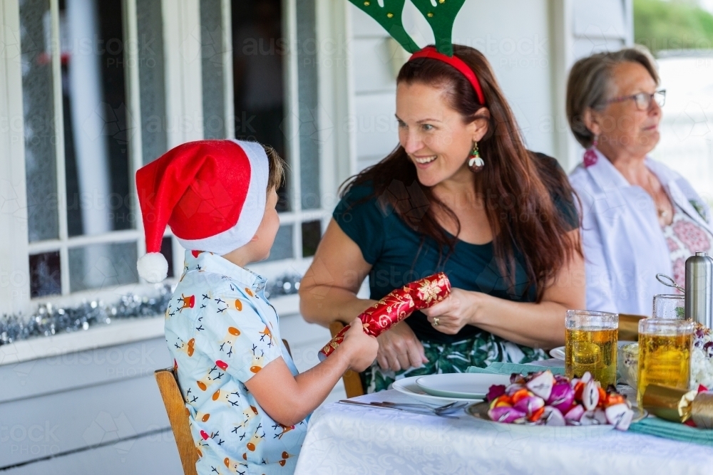 Image of Mum with her kid ready to pop a Christmas cracker before lunch ...