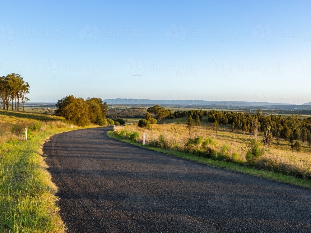 Image of Narrow country road in hills with golden sunlight at sunset ...