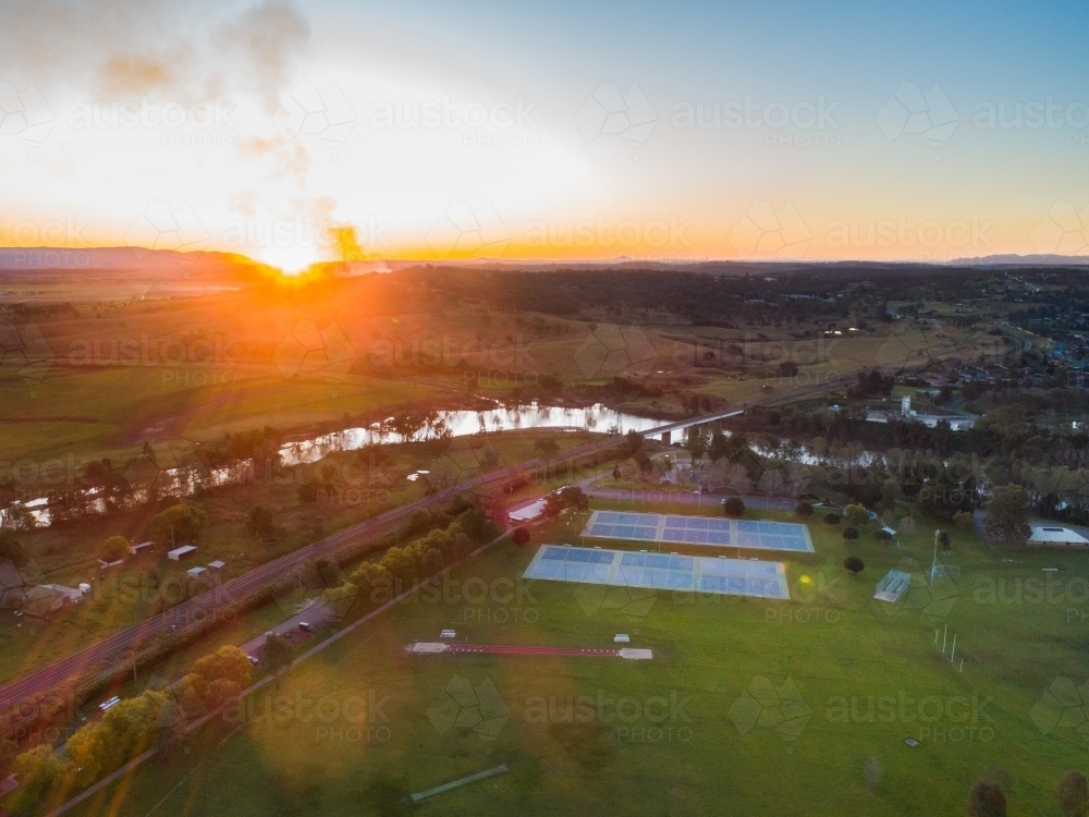 Image of Netball courts in park beside river at sunset with smoke in ...