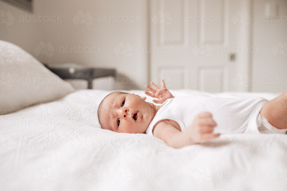 Image of Newborn baby boy lying on his back on the bed - Austockphoto