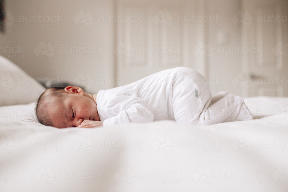 Image of Newborn baby boy sleeping on his tummy on the bed - Austockphoto