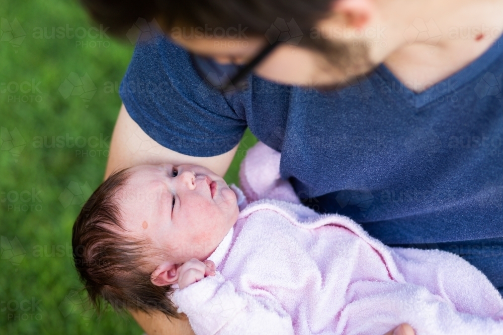 Image of Newborn baby girl looking up at her father who is cuddling her ...