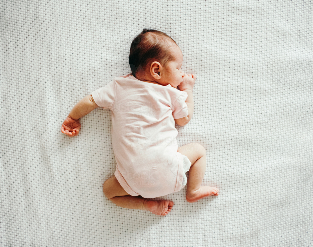 Image of Newborn baby sleeping on her tummy on the bed - Austockphoto