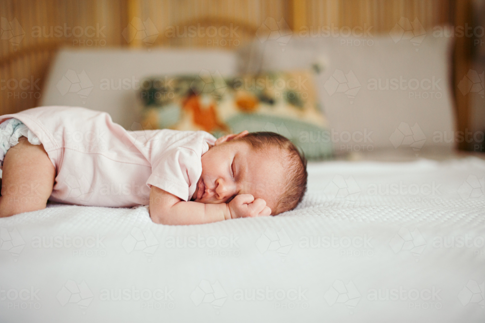Image of Newborn baby sleeping on her tummy on the bed - Austockphoto
