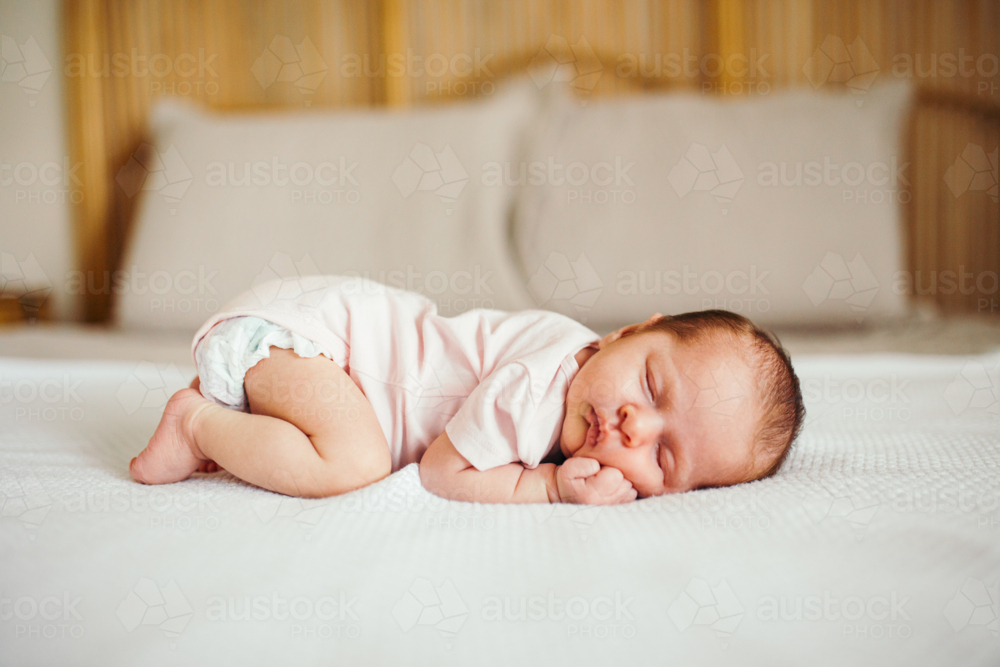 Image of Newborn baby sleeping on her tummy on the bed - Austockphoto