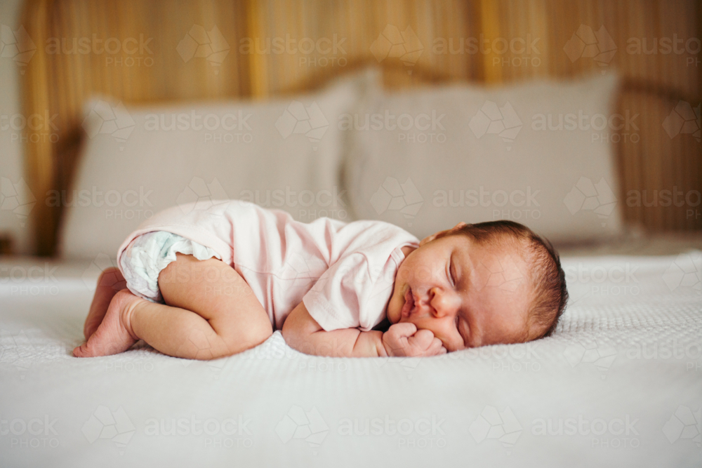 Image of Newborn baby sleeping on her tummy on the bed - Austockphoto