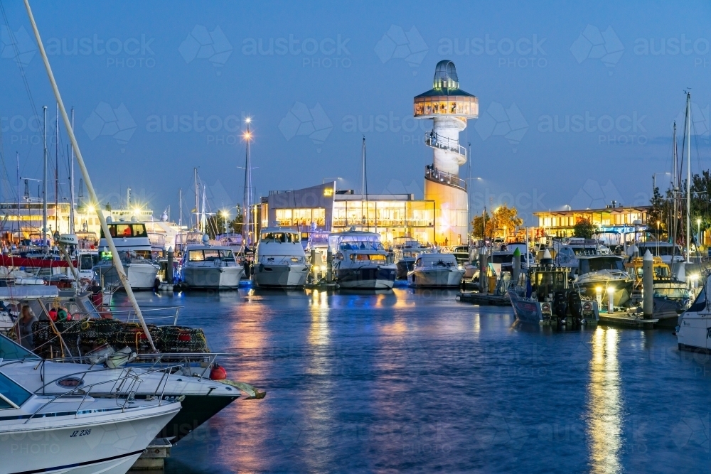 Image of Night time view of a boat marina and lookout tower - Austockphoto