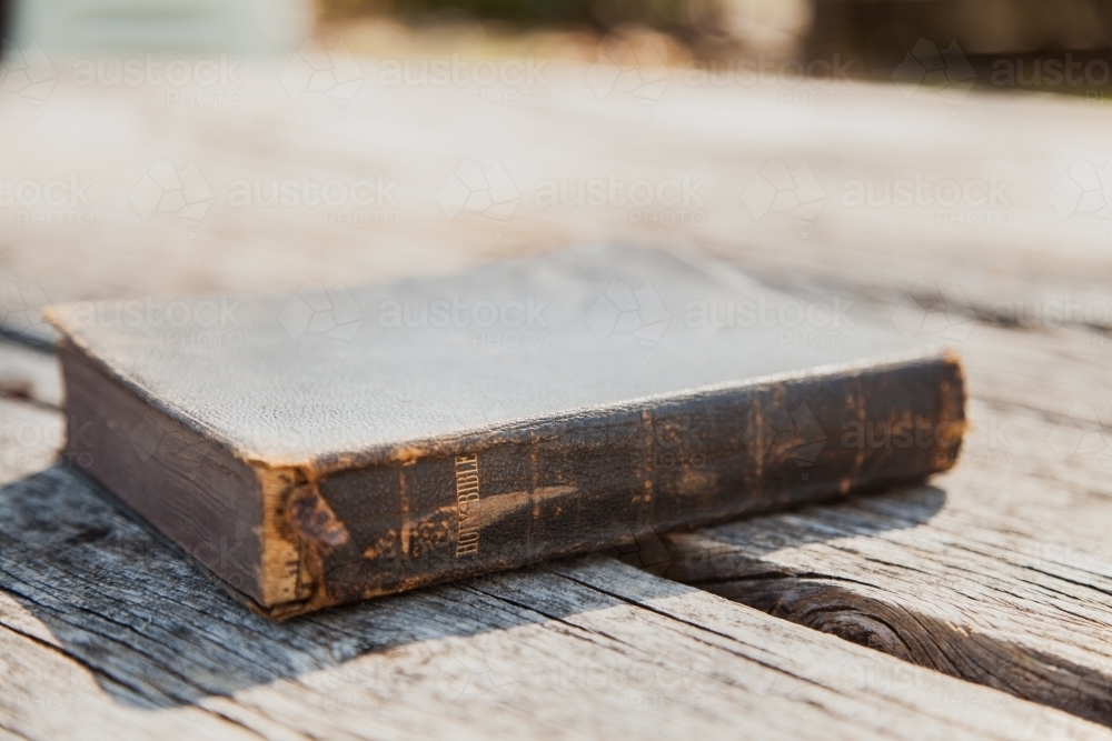 Image of Old holy bible on wooden table outside - Austockphoto