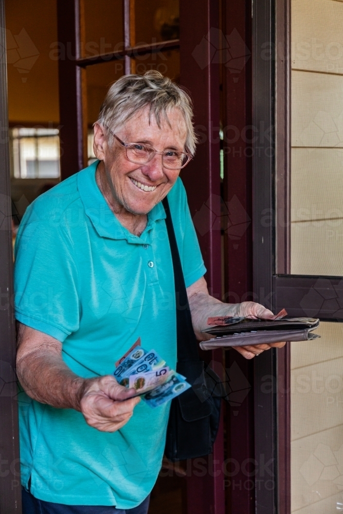 Image of Old person at front door handing over cash from wallet ...
