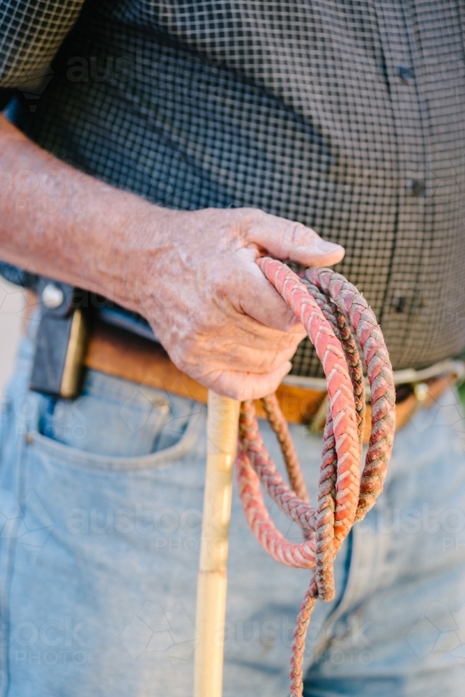 Image of old retired cowboy holding a whip - Austockphoto
