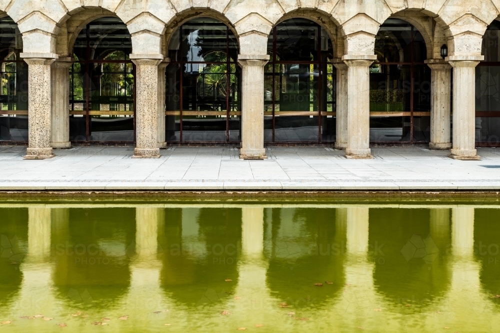 Image of Old stone building arches reflecting in pond. - Austockphoto