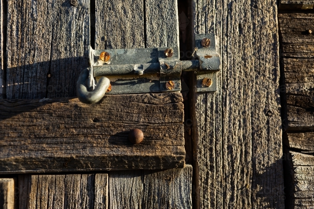 Image of Old weather worn wooden stables with latch keeping door closed ...