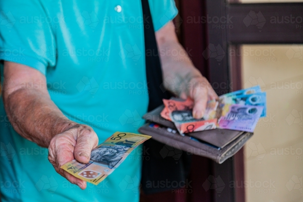 Image of Older woman handing over fifty dollar note - Austockphoto