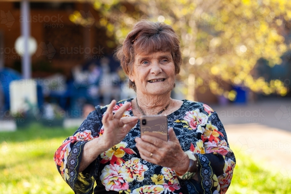 Image of Older woman using technology outside in her backyard ...
