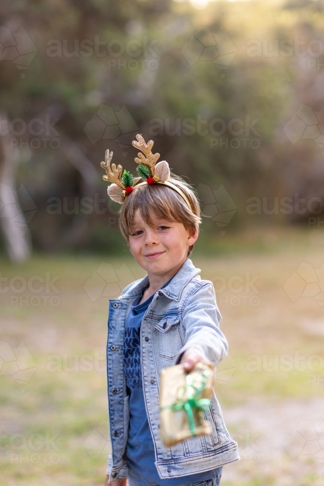 Image of one boy proffering a Christmas gift wrapped in dull gold paper ...