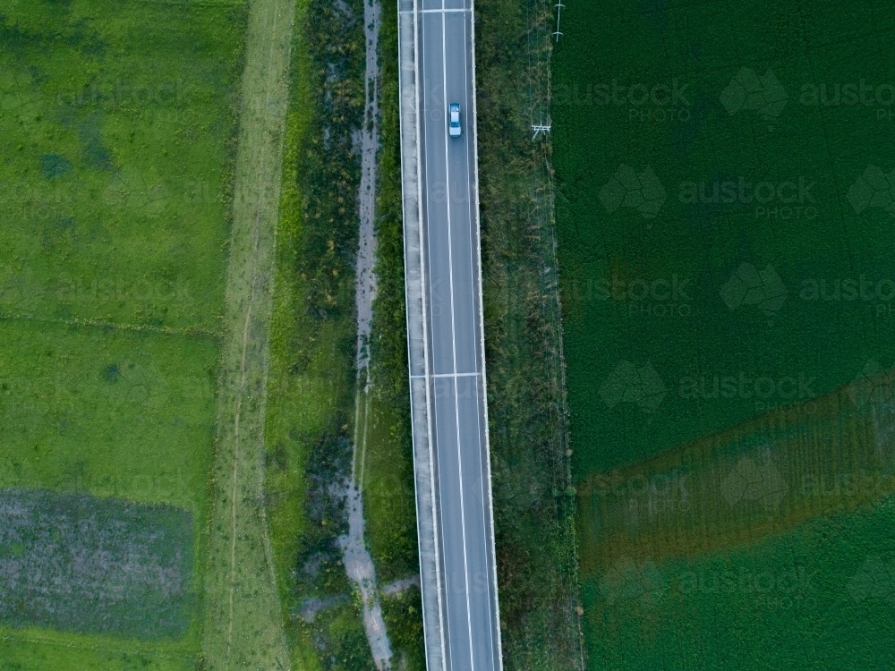 Image of One car on road becoming bridge over floodplain with crop ...