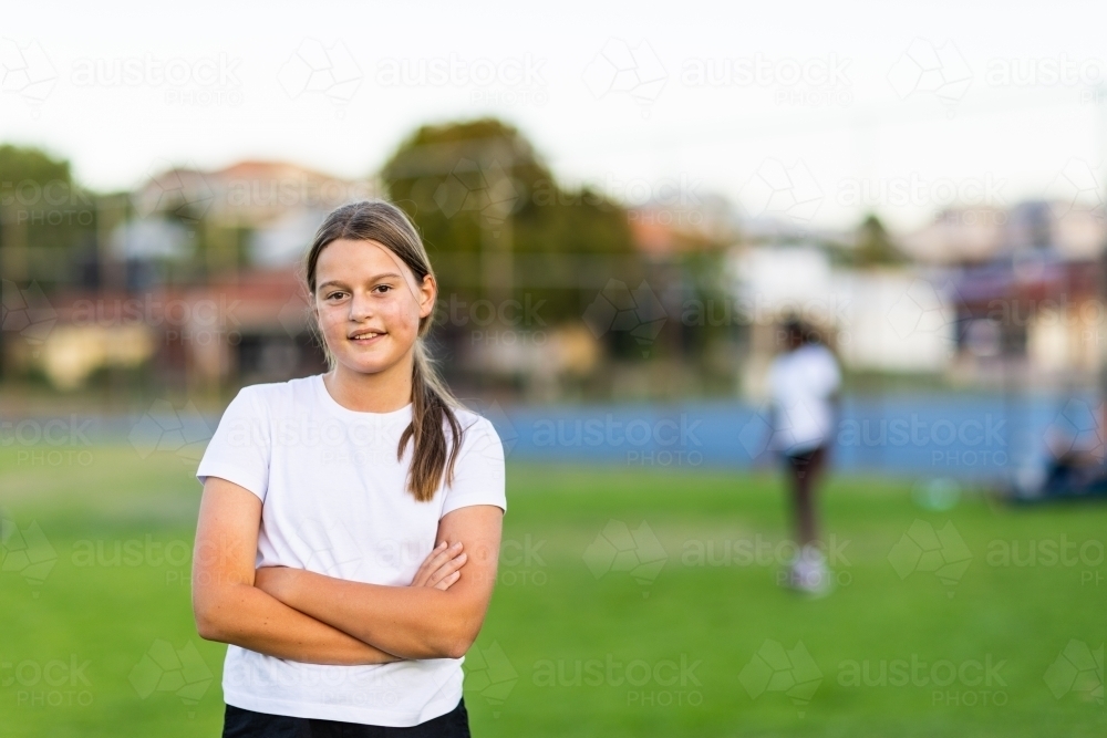 Image of one tween girl standing looking at camera with another child ...