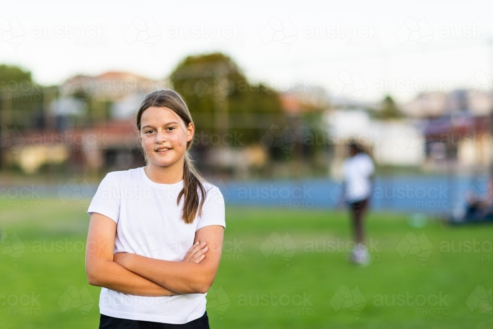 Image of one tween girl standing with arms crossed at the field with ...