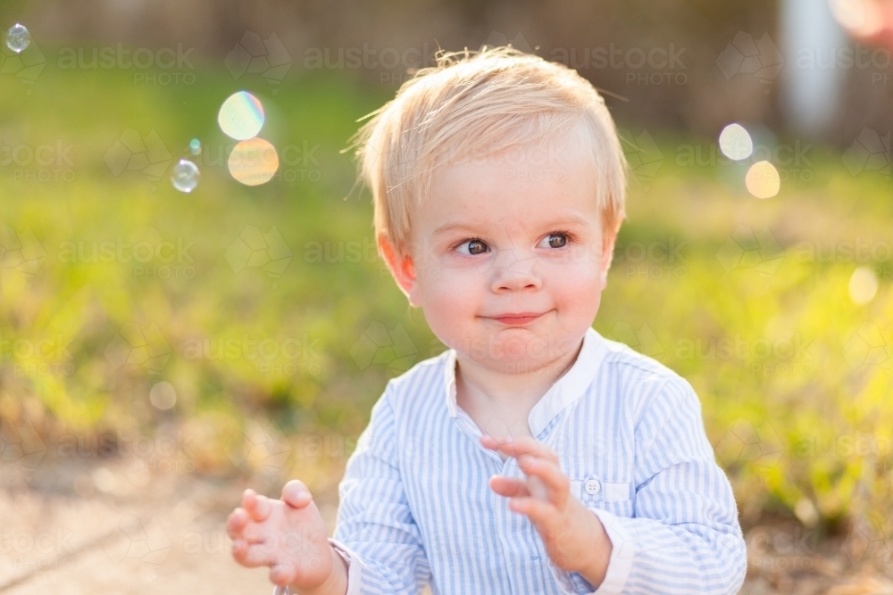 Image of One year old boy looking at bubbles trying to catch them ...