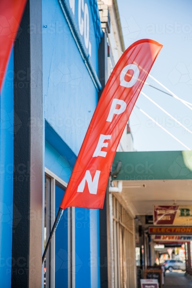 Image of Open flag sign outside shop in main street - Austockphoto