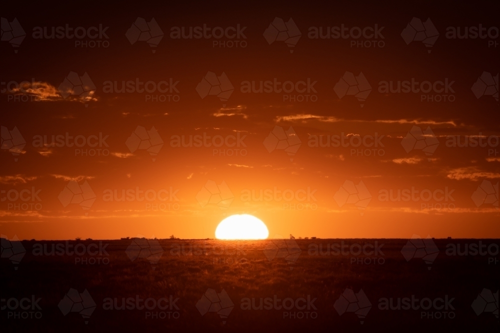 Image of Orange sun setting over rural landscape - Austockphoto