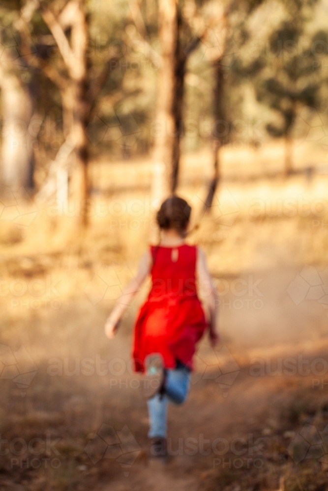 Image of Out of focus image of girl in pigtails running on farm kicking ...