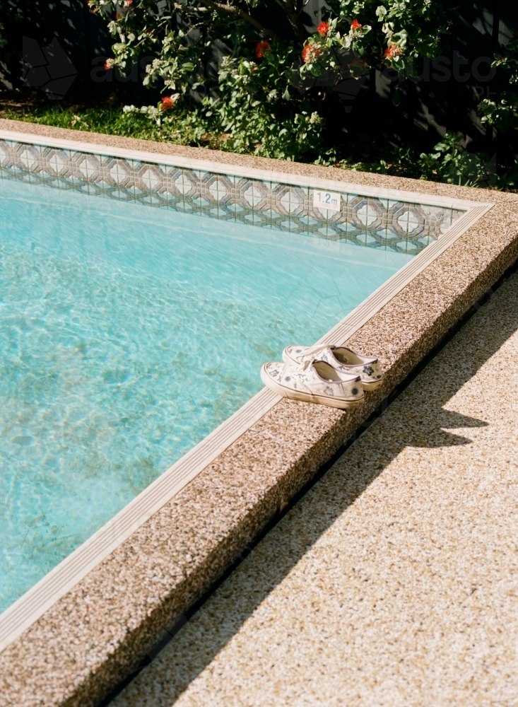 Image of outdoor swimming pool and a pair of sneakers on the poolside ...