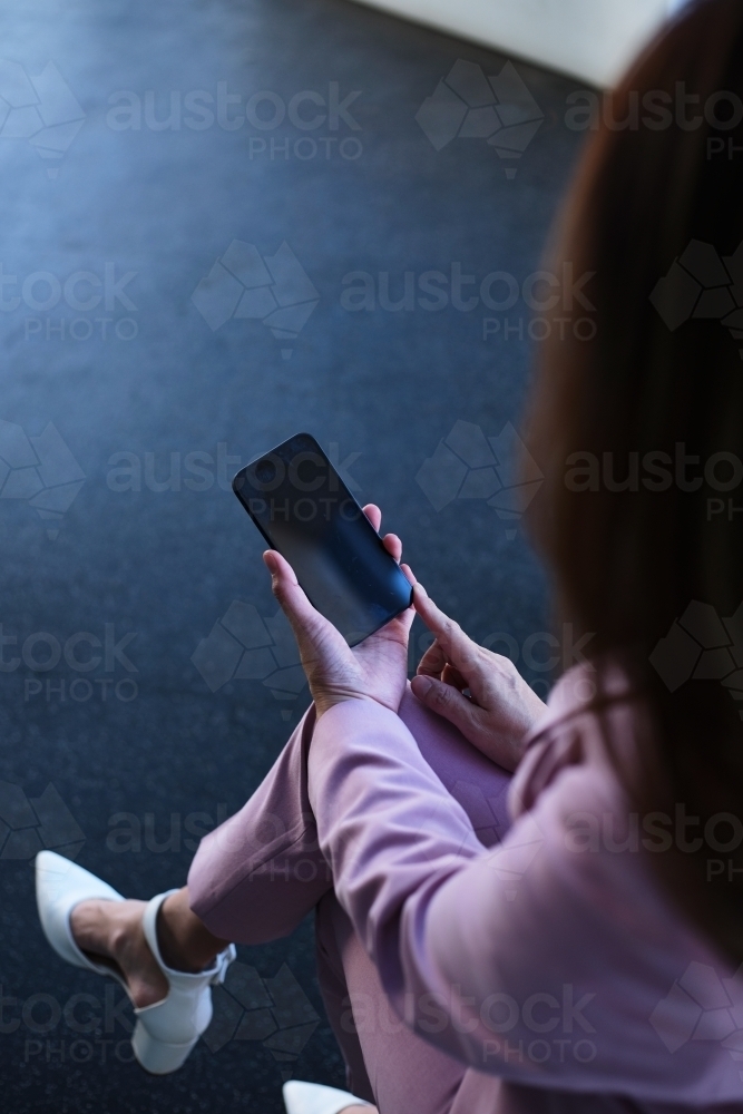 Image of Over the shoulder shot of woman typing on mobile phone ...