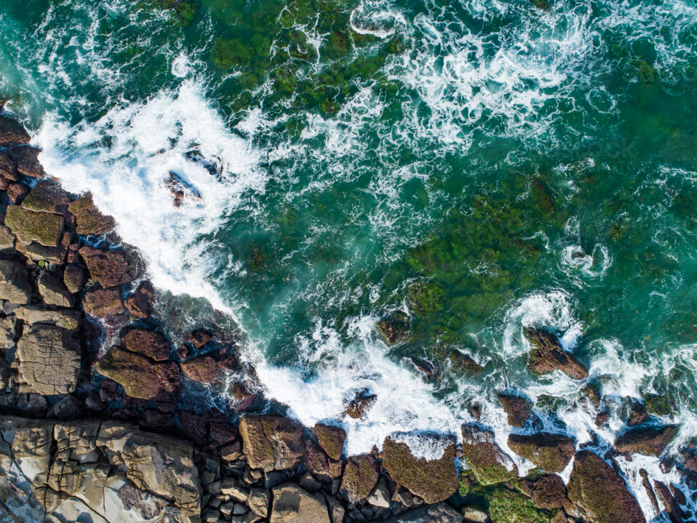 Image of Overhead coastal view of ocean waves crashing onto rock on the ...