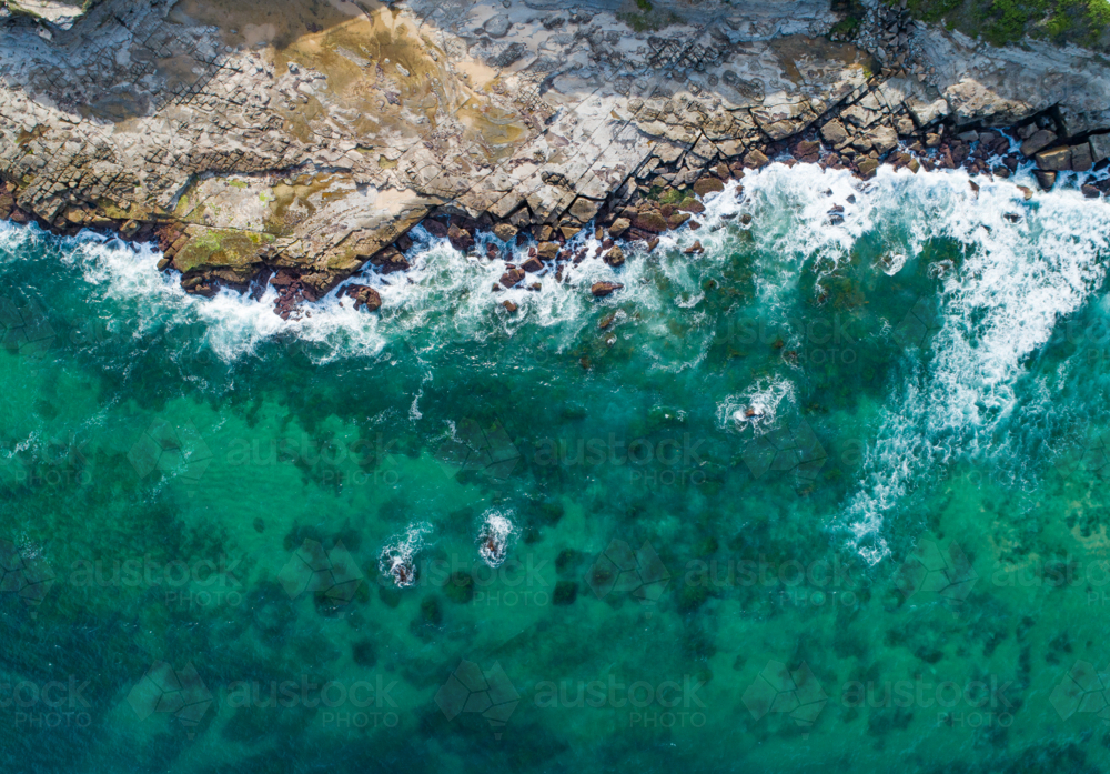 Image of Overhead coastal view of ocean waves crashing onto rocks on ...