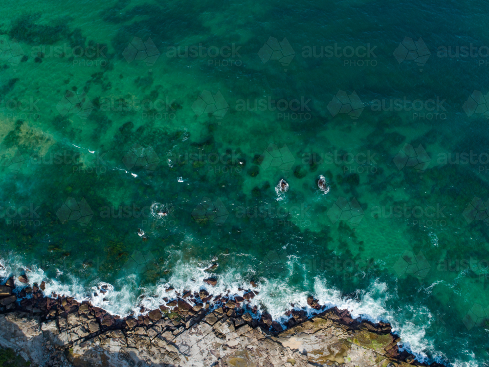 Image of Overhead coastal view of ocean waves crashing onto rocks on ...