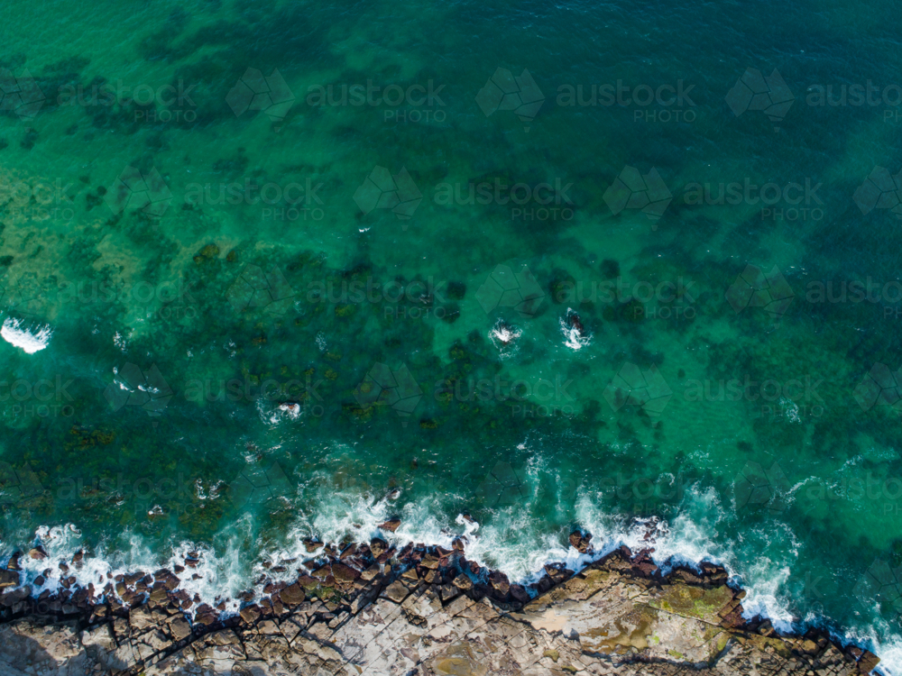 Image of Overhead coastal view of ocean waves crashing onto rocks on ...