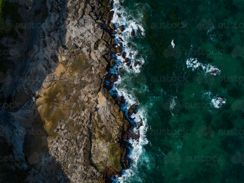 Image of Overhead coastal view of ocean waves crashing onto rocks on ...