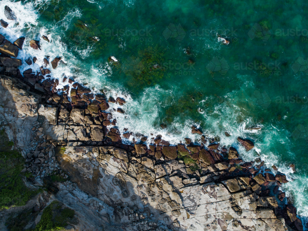 Image of Overhead coastal view of ocean waves crashing onto stony shore ...