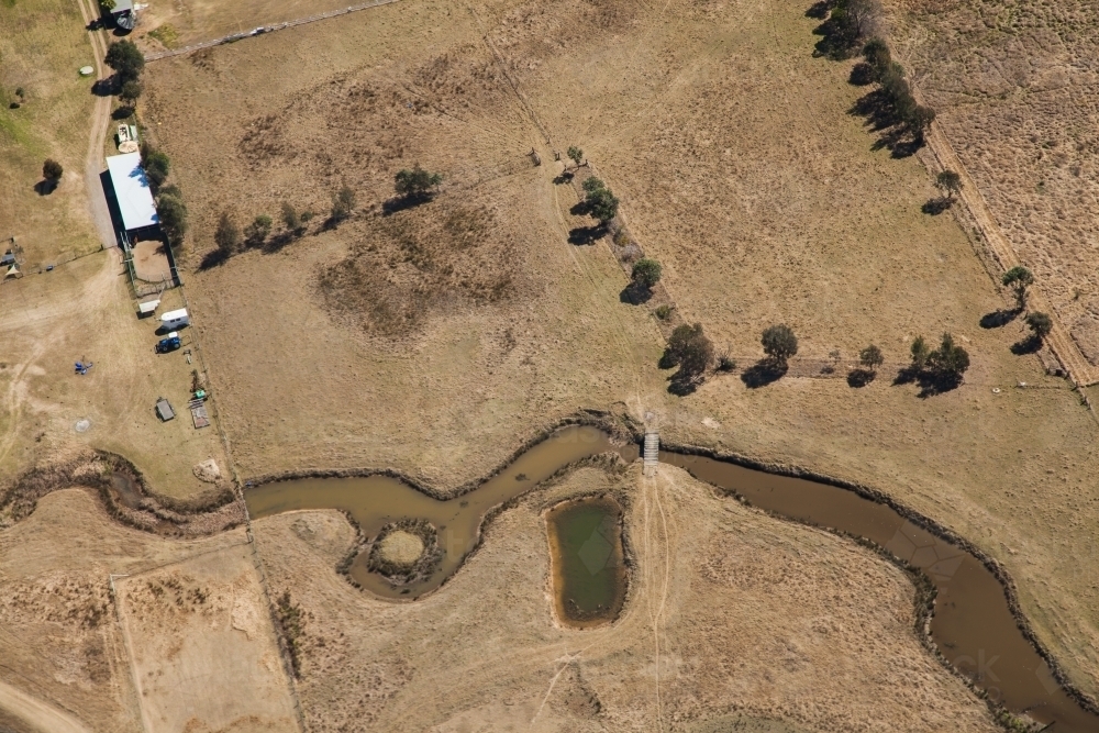 Image of Overhead view of dry paddocks of brown farmland with river and ...