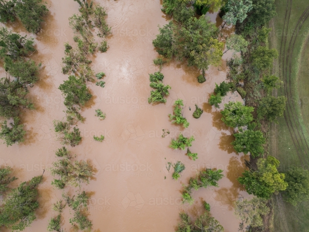 Image of Overhead view of rushing brown floodwaters overflowing river ...