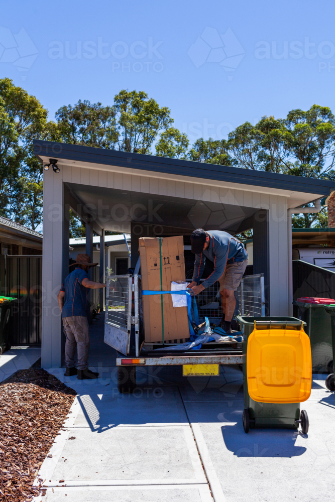 Image of Pair of Aussie tradies unloading solar panels from back of ...