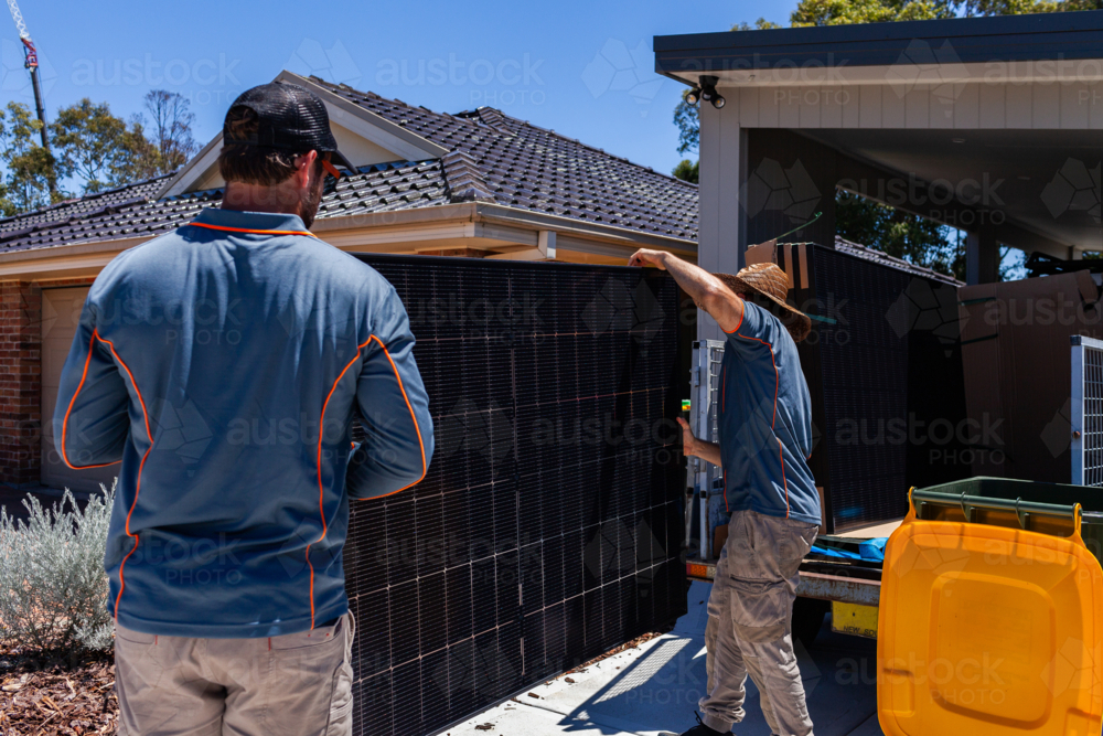 Image of Pair of Aussie tradies unloading solar panels from back of ...
